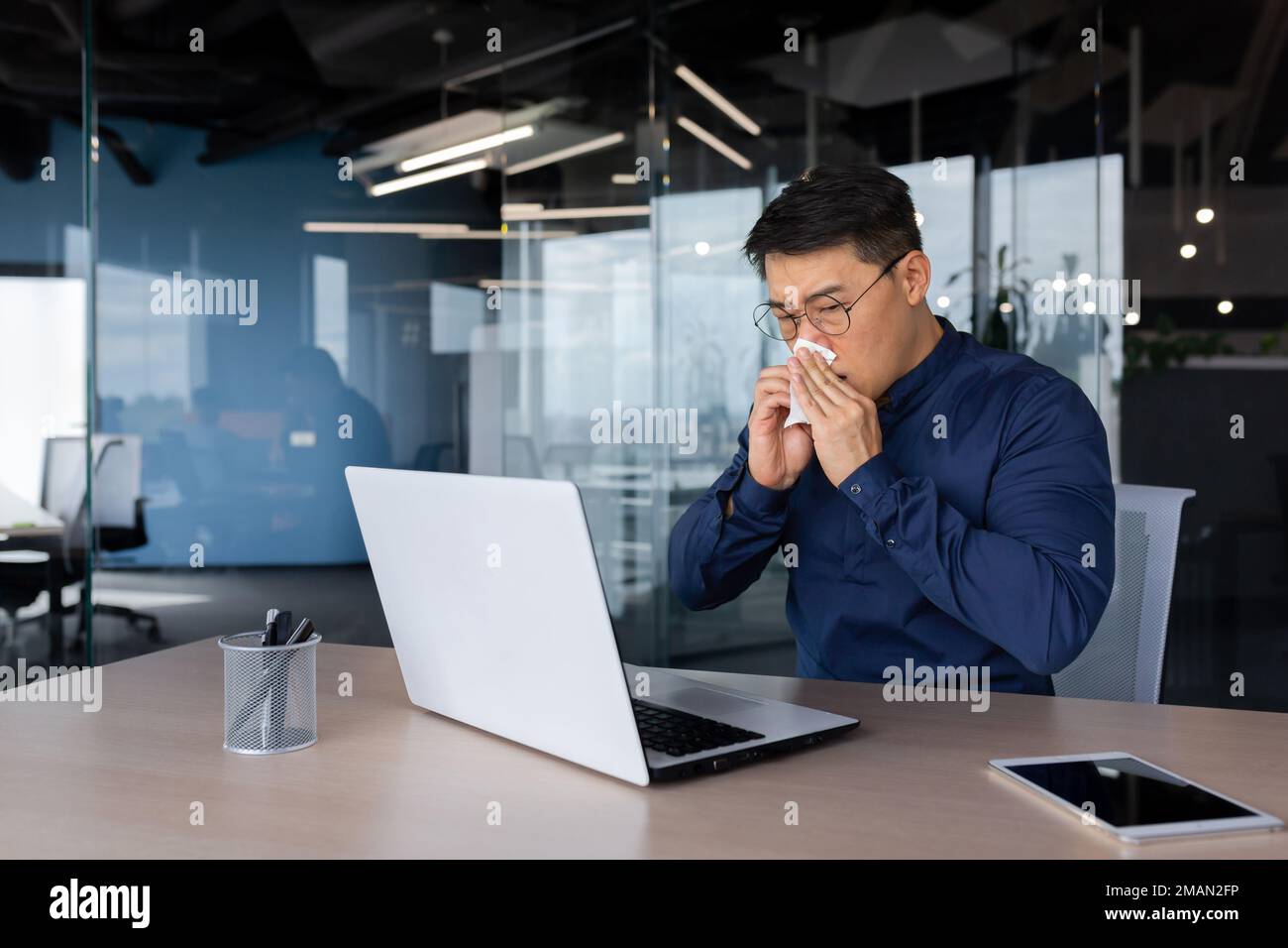 Sick asian man at work, man sneezing has fever and runny nose ...