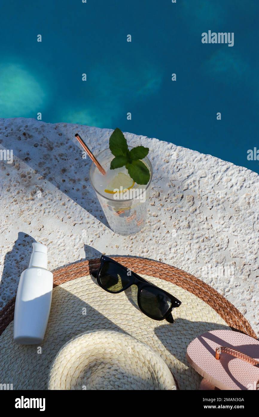 Refreshing glass of water with lemon, straw hat, sunglasses and ...