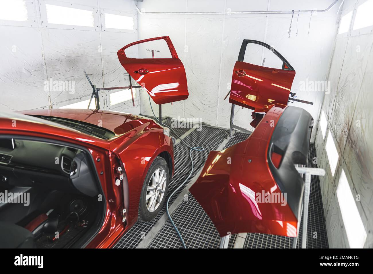 A luxury red car in a paint shop with its doors removed for a fresh ...