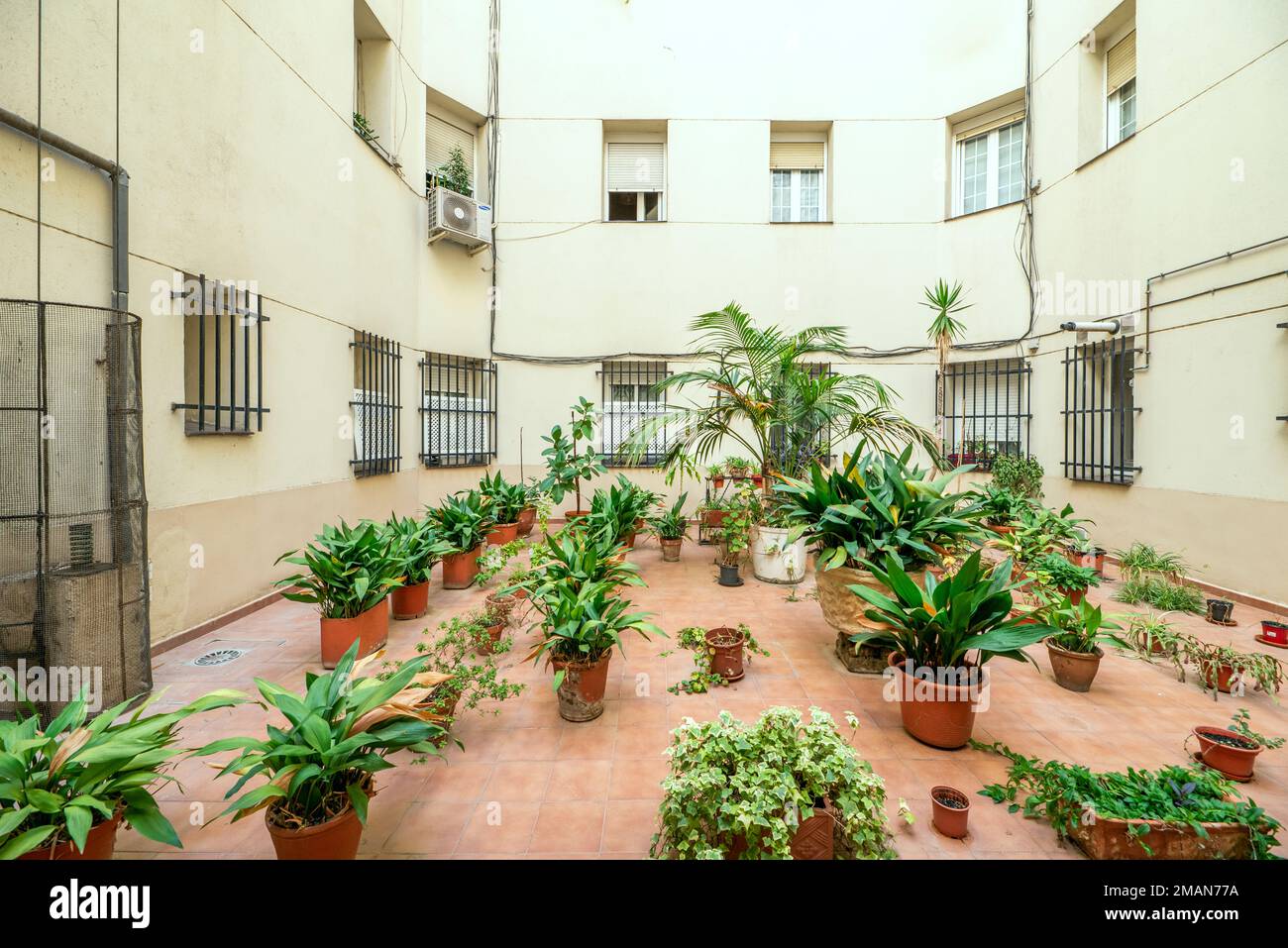 An inner courtyard of a building with a multitude of potted plants and ...