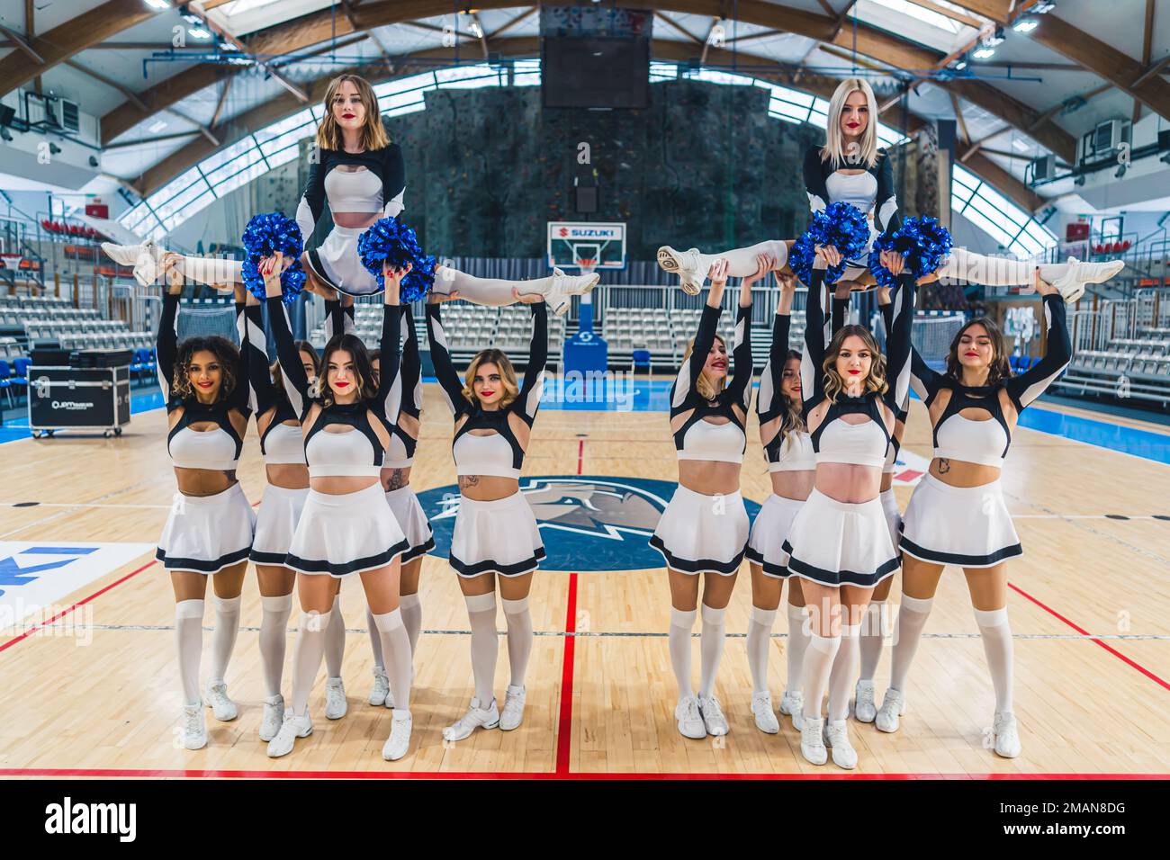 Front view of cheerleaders in uniforms posing and holding two members ...