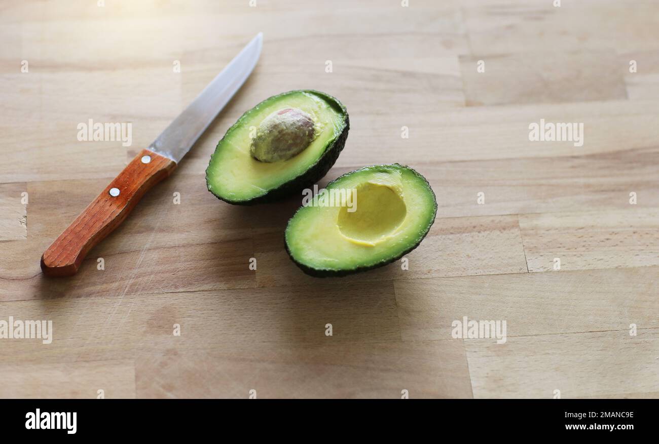 Two slices of fresh organic hass avocado on wooden table background ...