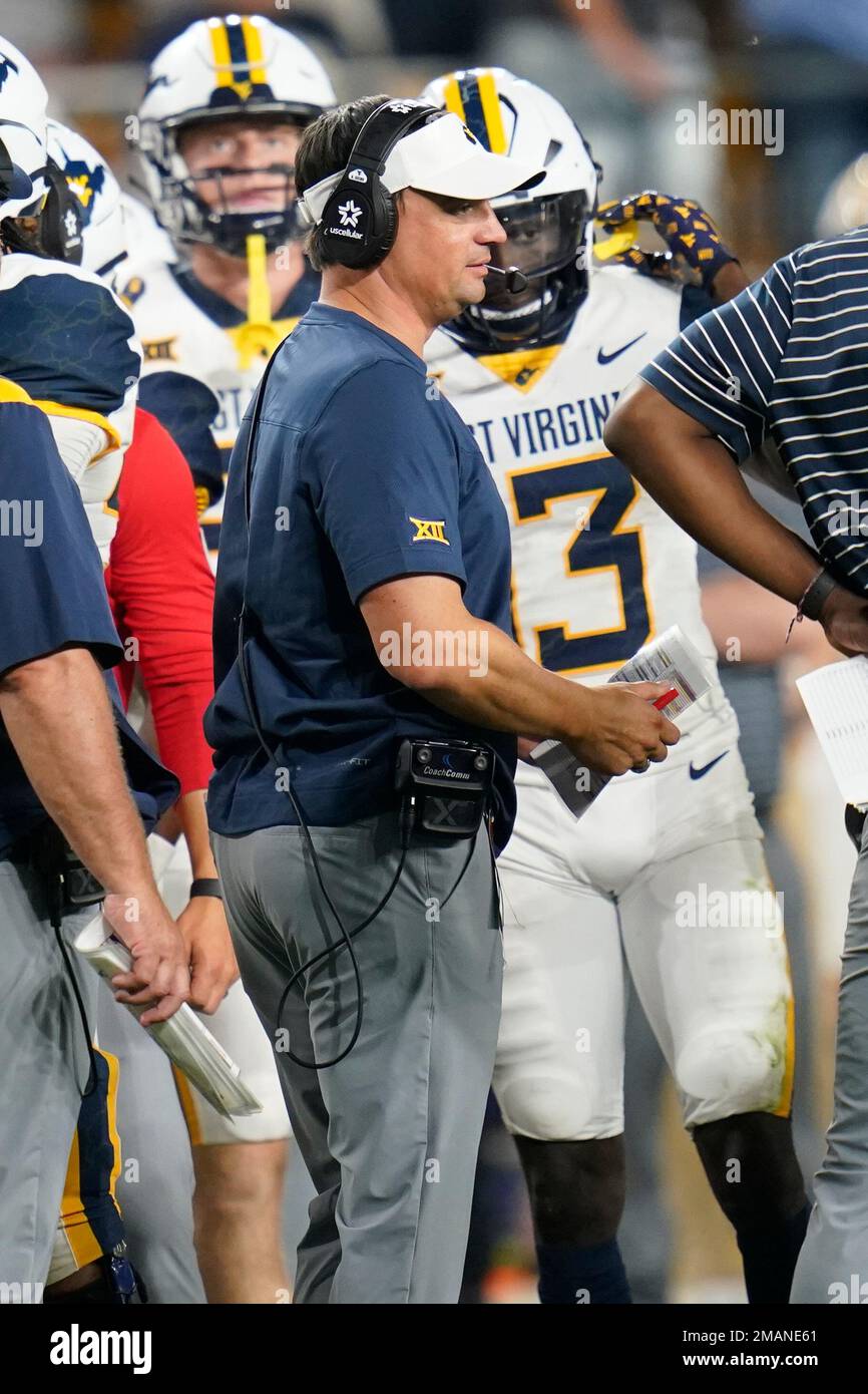 West Virginia head coach Neal Brown, in white visor, works the sideline ...