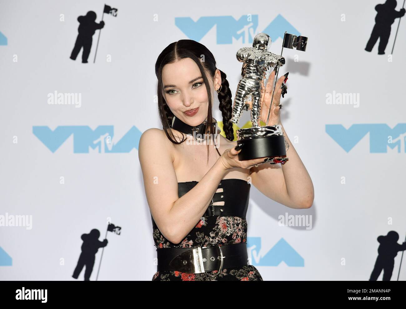Dove Cameron poses in the press room with her award for best new artist ...