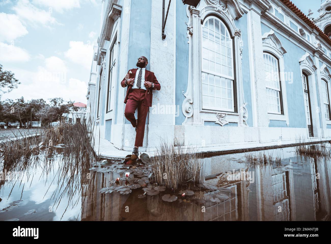 An imposing African bald man with a full-grown beard wearing a red ...