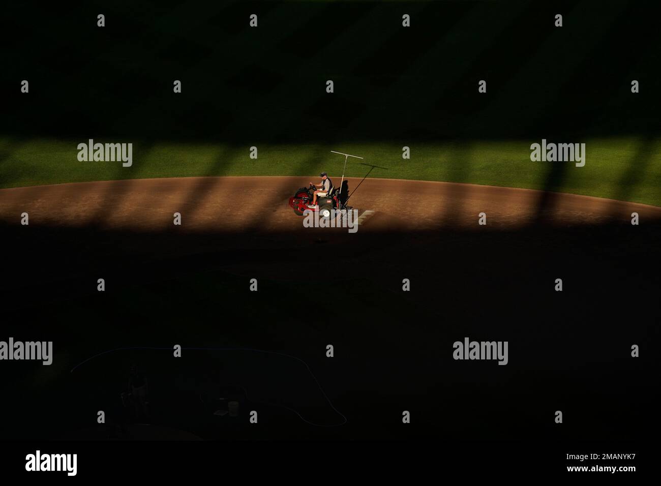A grounds crew member prepares the field before of a baseball game ...