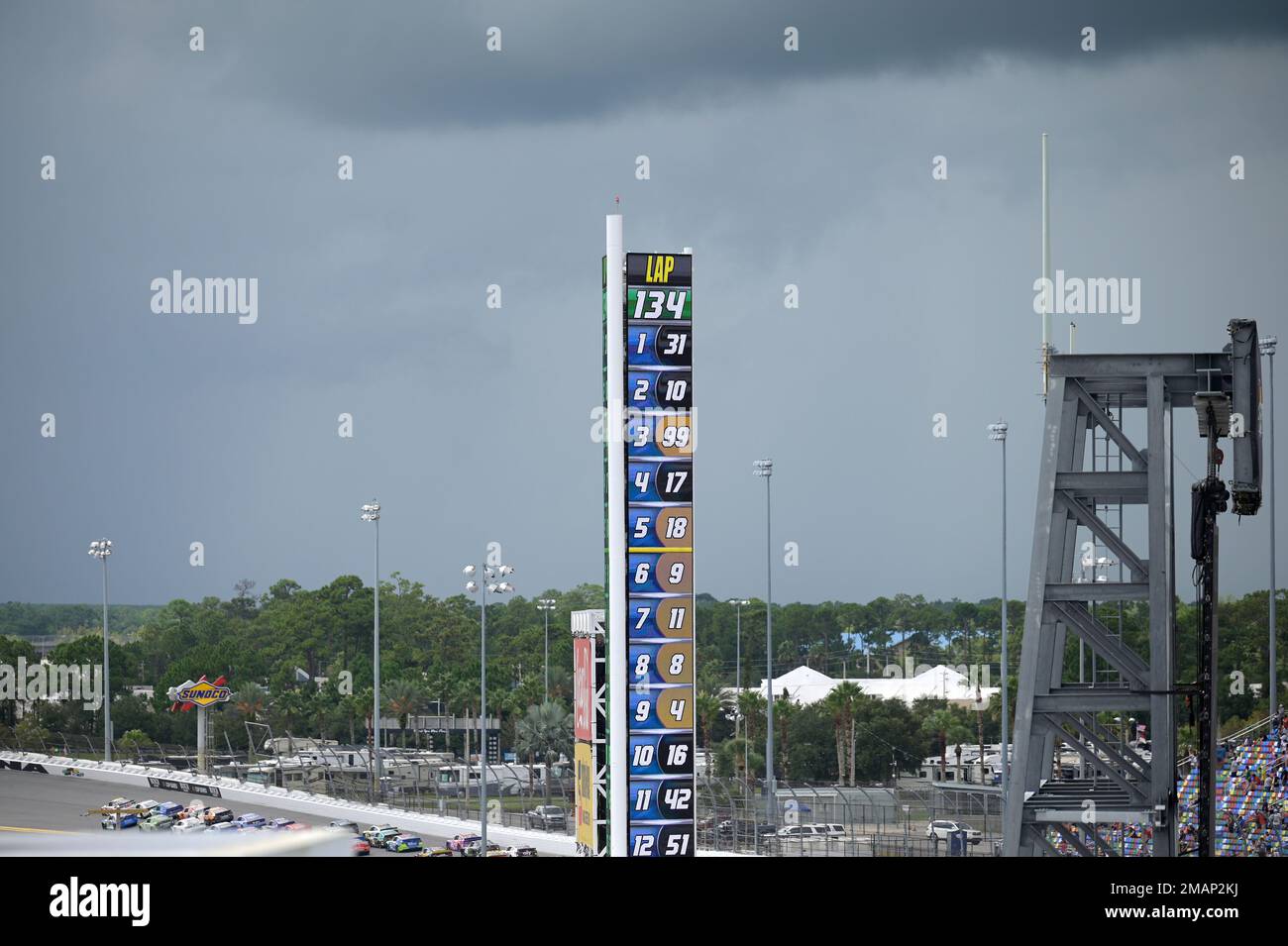 Storms approach as cars make their way through the first turn behind a ...