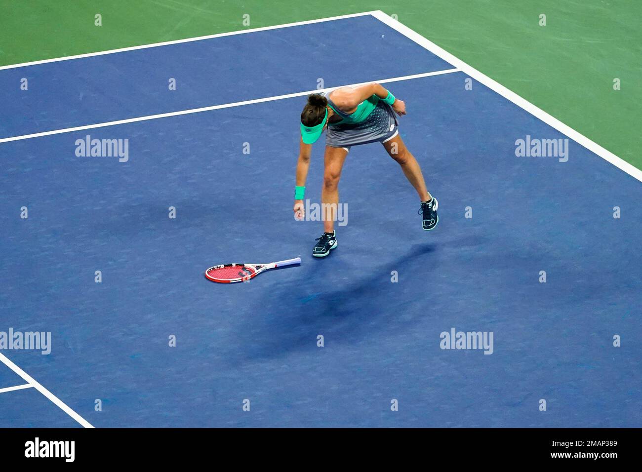 Alize Cornet, of France, picks her racket she tossed during a match ...