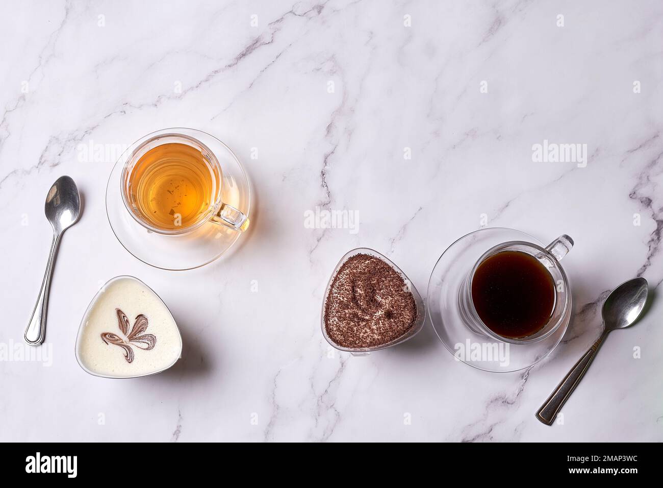 some teas and spoons on a marble counter top, with two cups filled with ...
