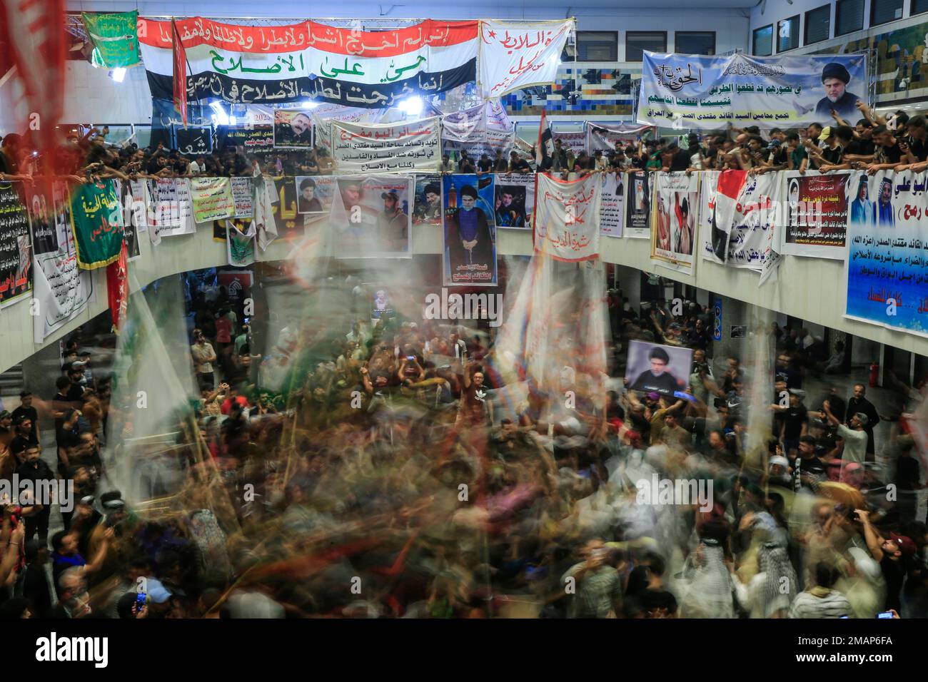 FILE - Followers of Shiite cleric Muqtada al-Sadr hold posters with his ...