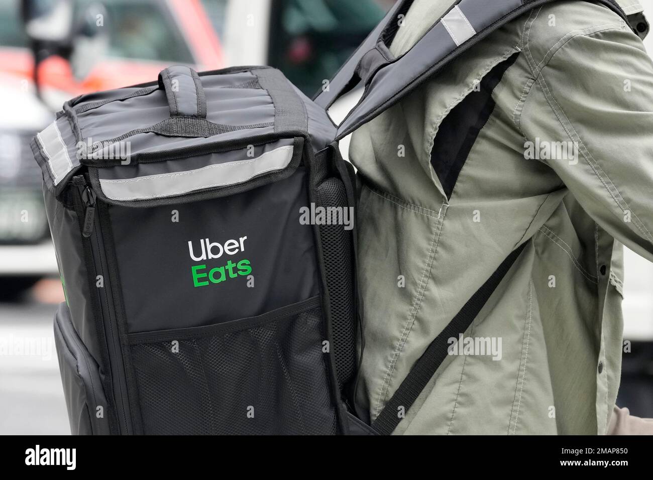 An Uber Eats delivery person rides a bicycle through a commercial ...