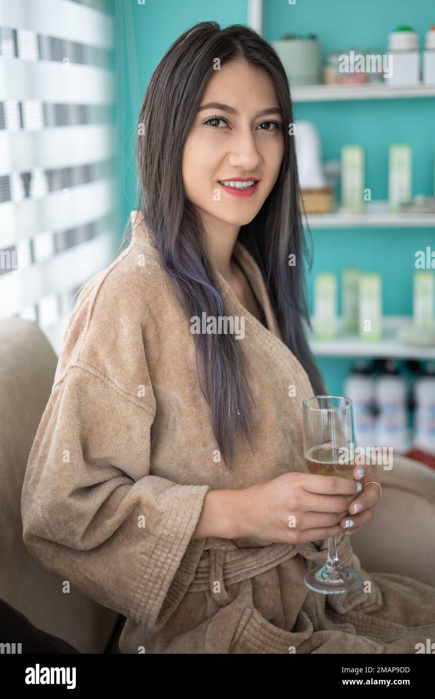 natural beauty of young latin model with black hair enjoying a glass of champagne while wearing ...