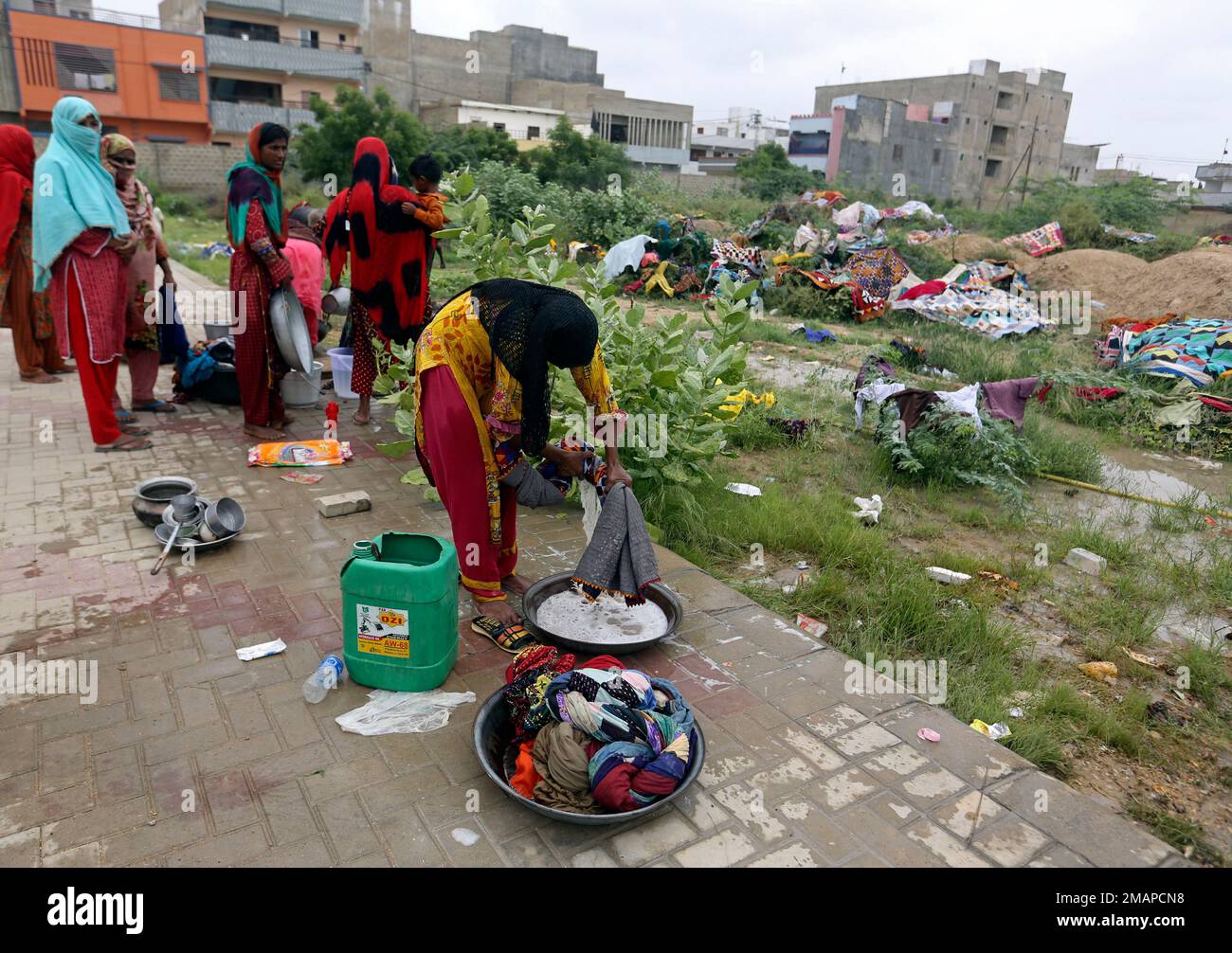 Pakistani women wash clothes on the grounds of a government college ...