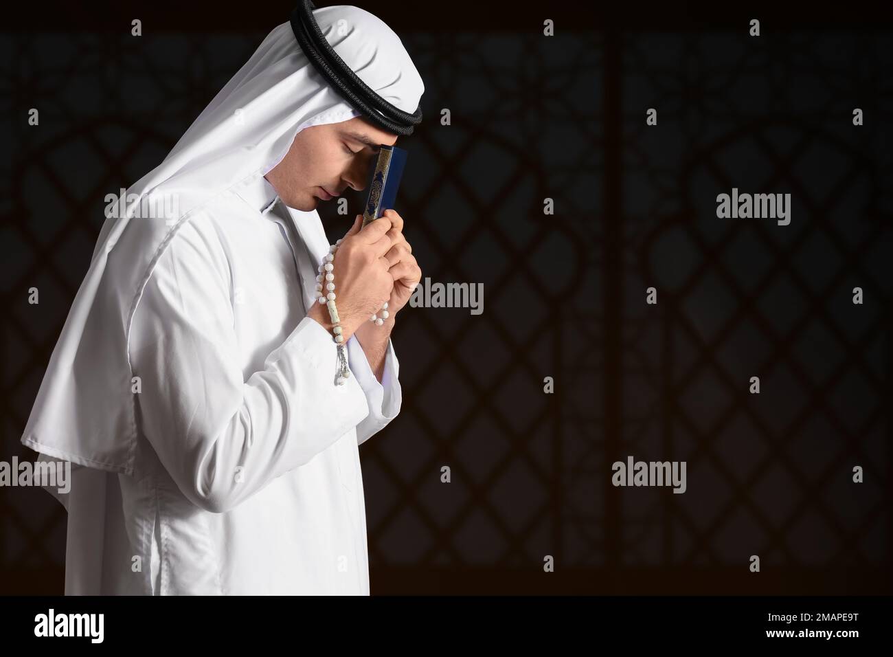 Praying Muslim man with Koran on dark background Stock Photo - Alamy