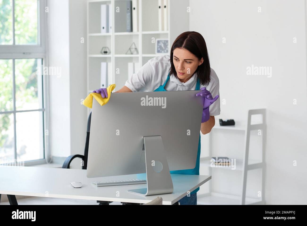 Female janitor wiping computer in office Stock Photo - Alamy