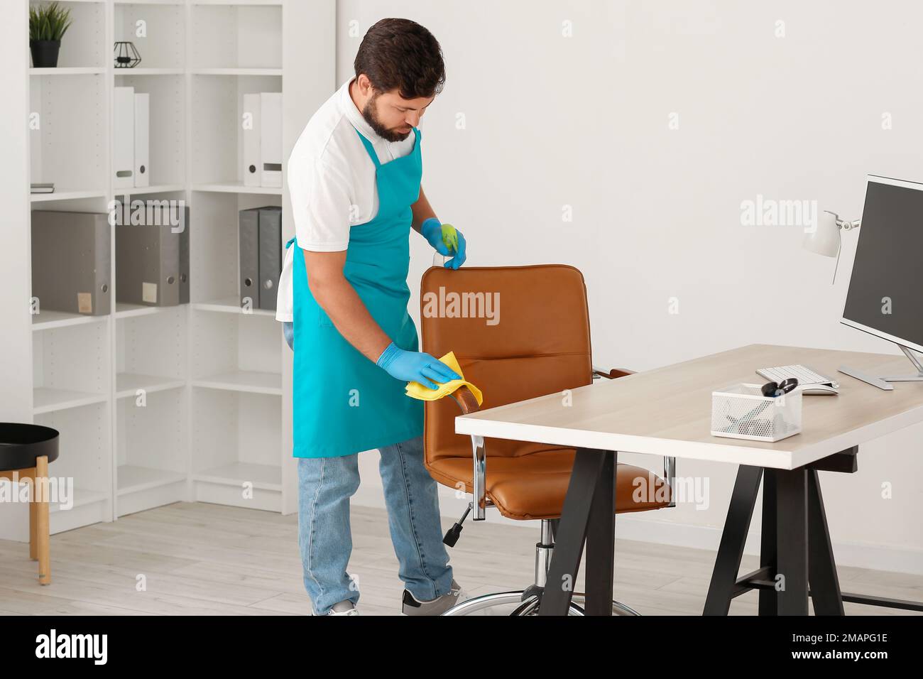 Male janitor cleaning chair in office Stock Photo - Alamy
