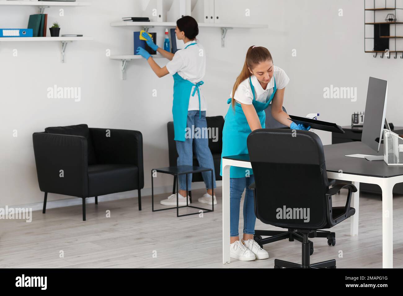 Female janitor cleaning desk in office Stock Photo - Alamy