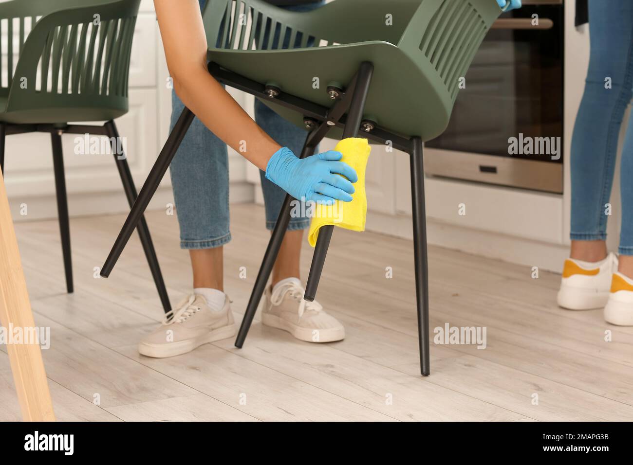 Female janitor cleaning chair in kitchen Stock Photo - Alamy