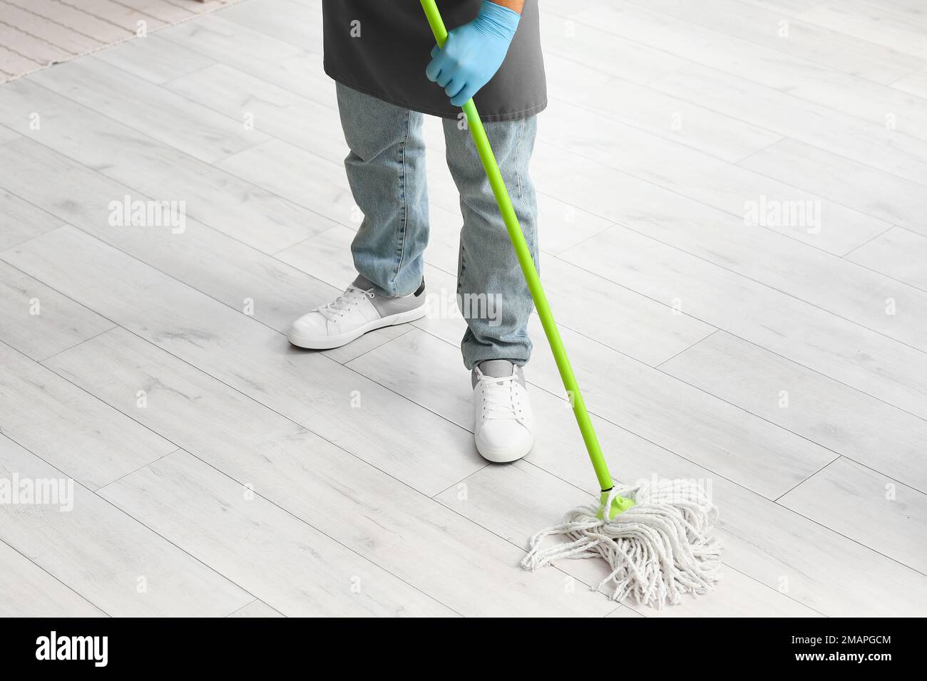 Male janitor mopping floor in living room Stock Photo - Alamy