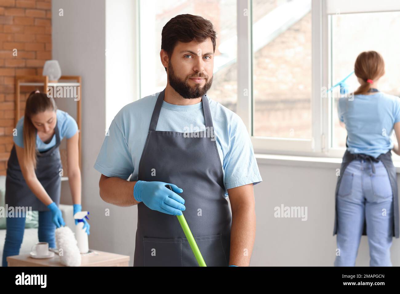 Male janitor with mop in living room Stock Photo - Alamy