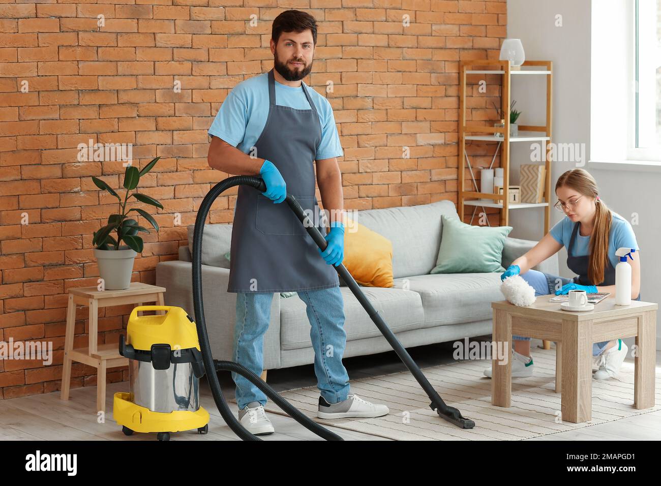 Male janitor hoovering carpet in living room Stock Photo - Alamy