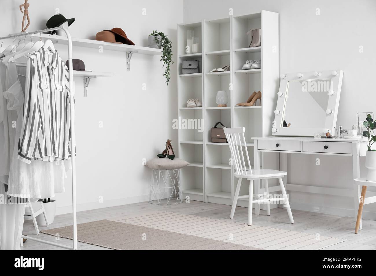 Interior of stylish dressing room with table, shelving unit and clothes ...