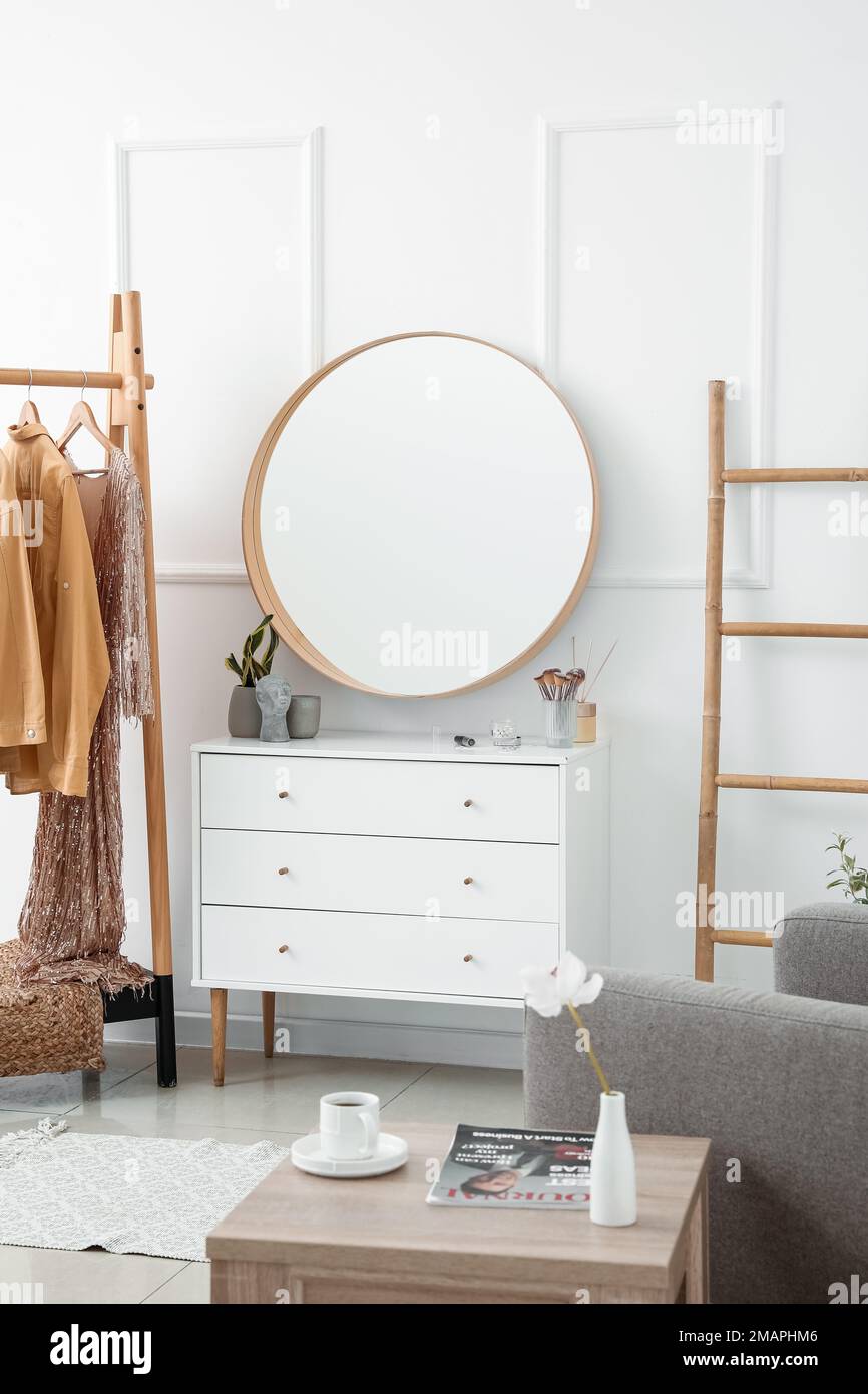 Interior of stylish dressing room with mirror, clothes and drawers ...