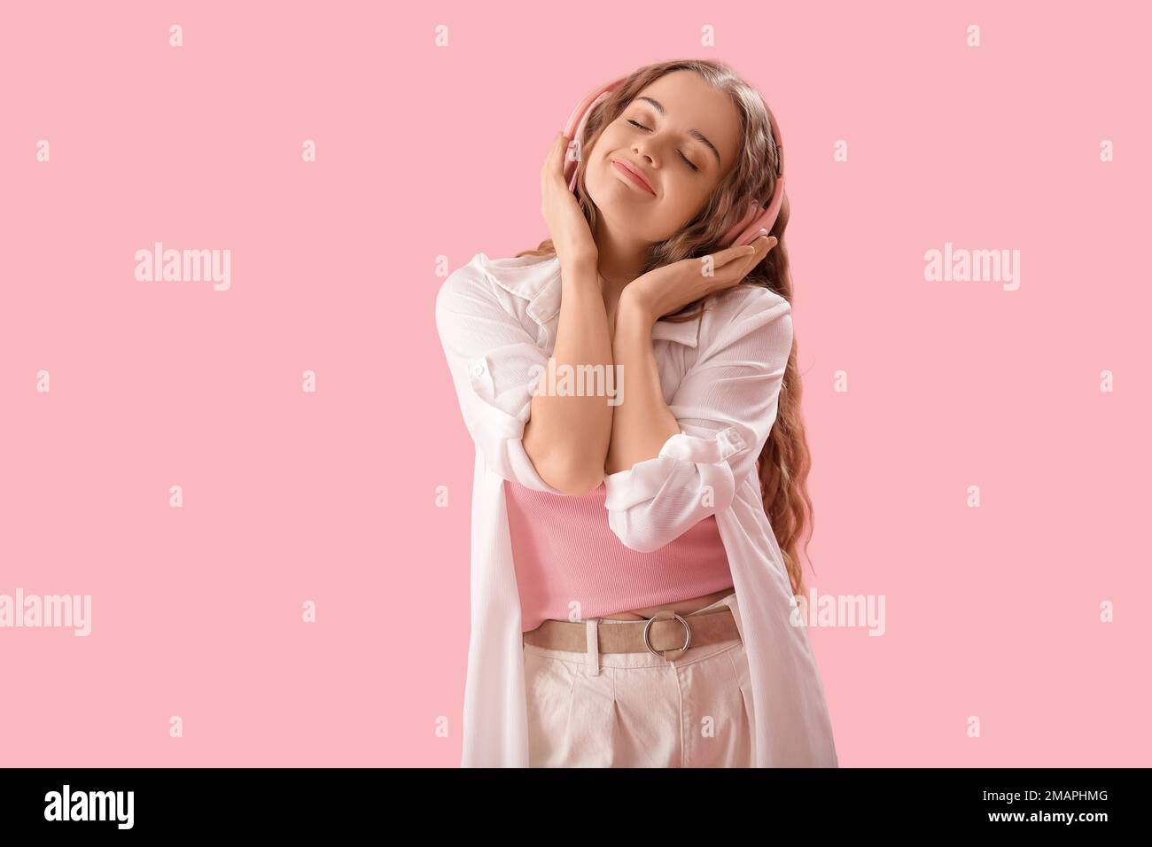 Young woman in headphones listening to music on pink background Stock ...