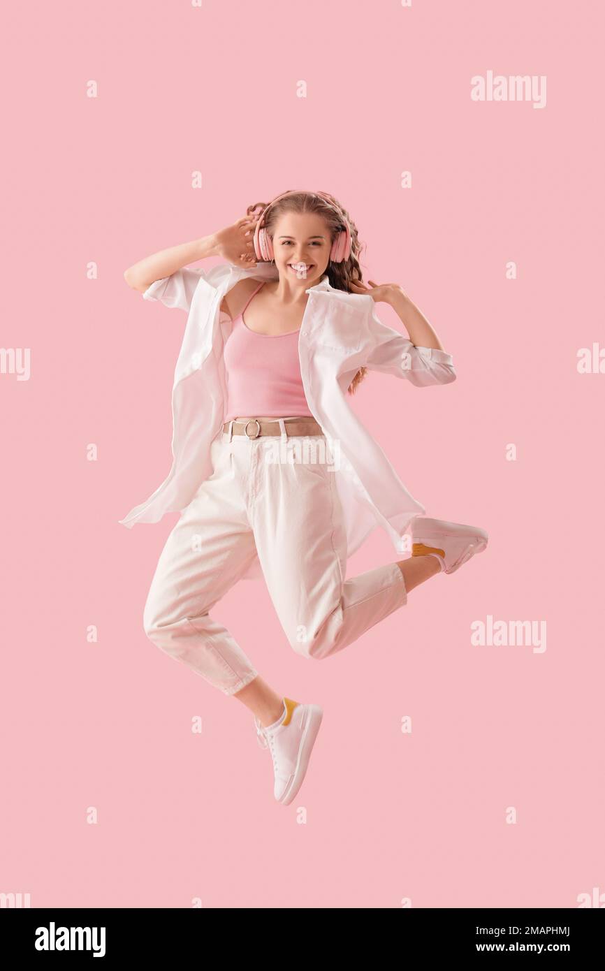 Young woman in headphones dancing on pink background Stock Photo - Alamy