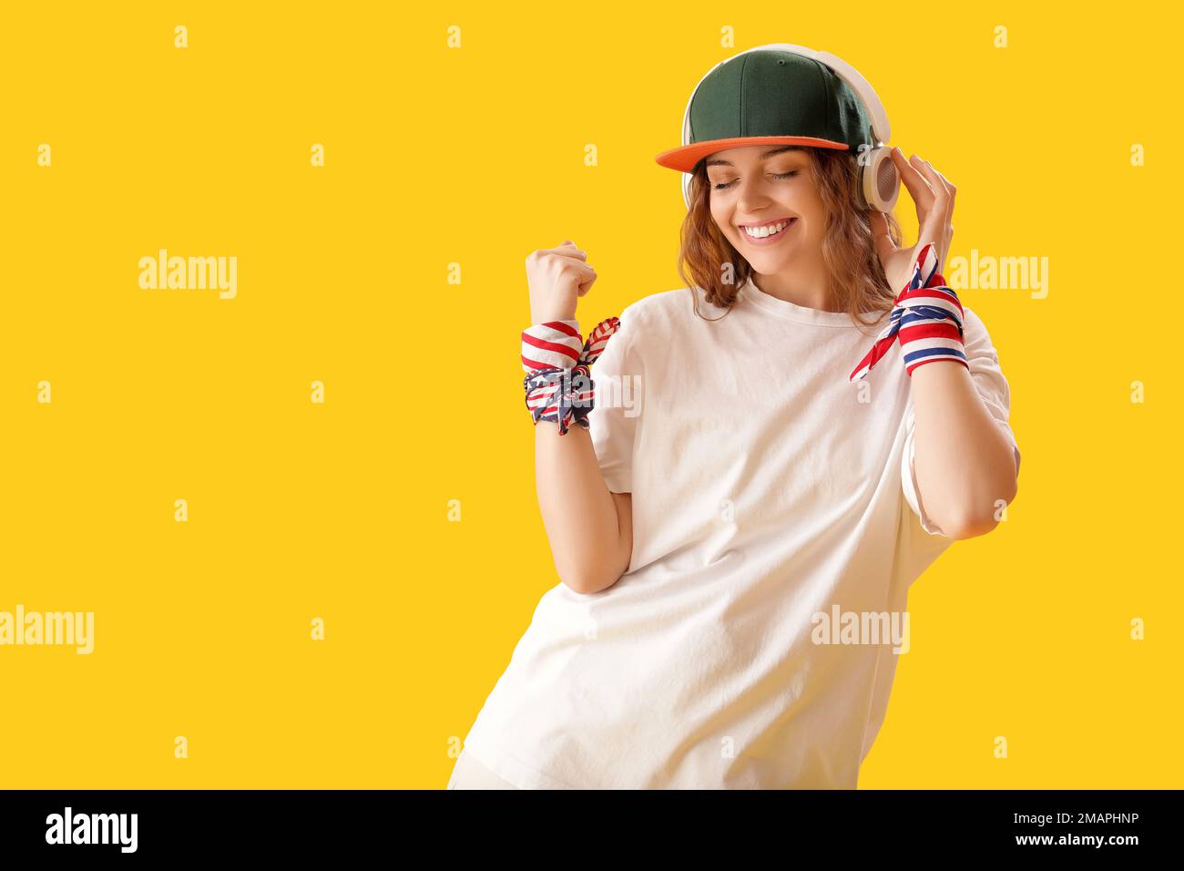 Female hip-hop dancer in headphones on yellow background Stock Photo ...