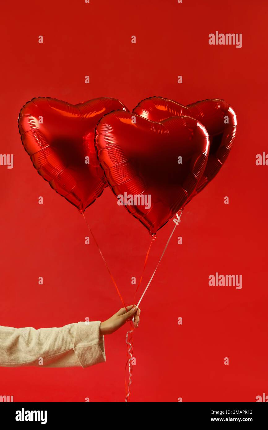 Woman with heart shaped balloons for Valentine's Day on red background ...
