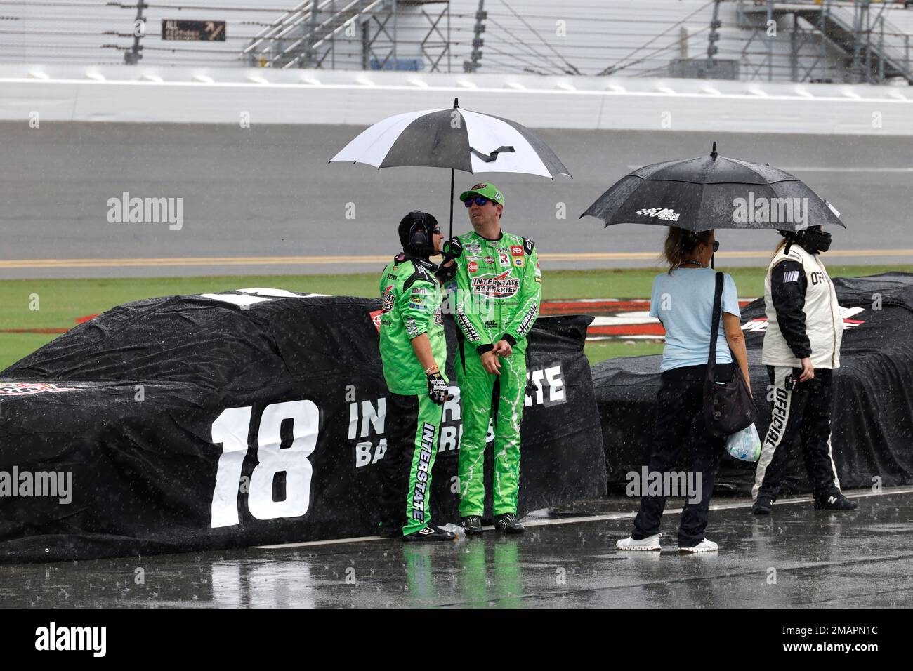 Kyle Busch stands next to his car on pit road after a thunderstorm ...