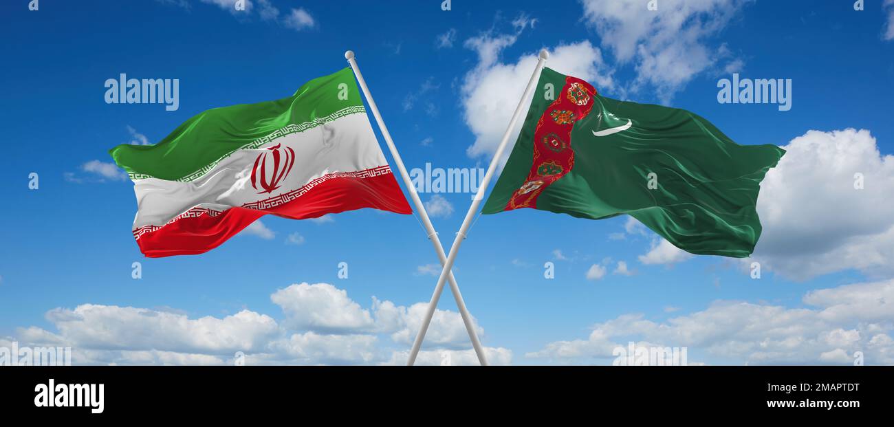 two crossed flags Turkmenistan and Iran waving in wind at cloudy sky ...