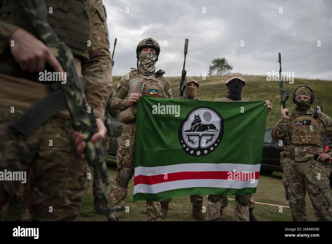 Volunteer soldiers pose with a flag of Chechen Republic of Ichkeria ...
