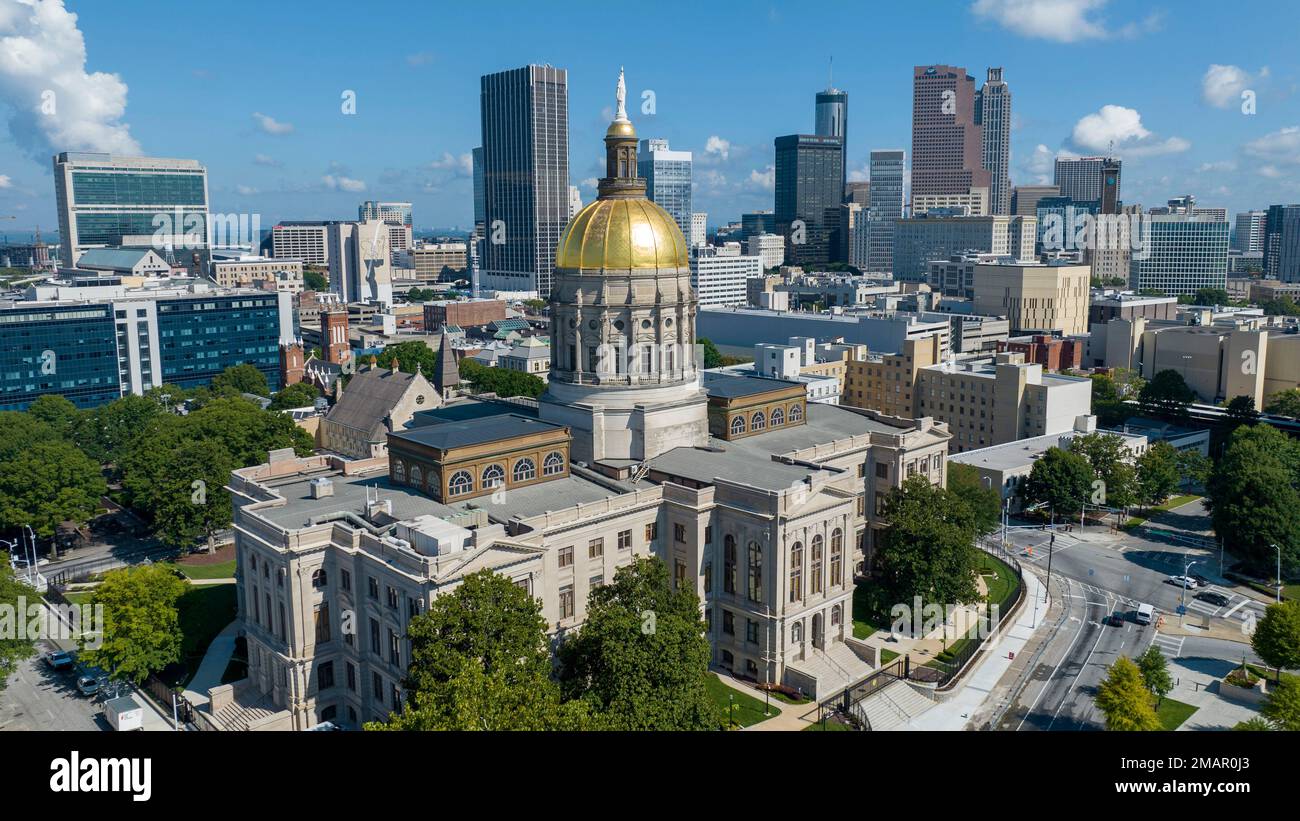 The gold dome of the Georgia State Capitol gleams in the sun in front ...
