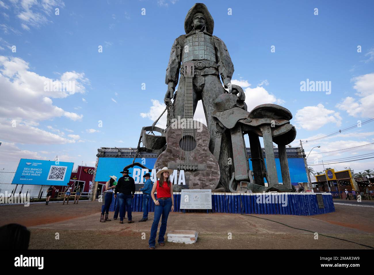 Visitors stand in front of a giant statue of a cowboy at the Barretos ...