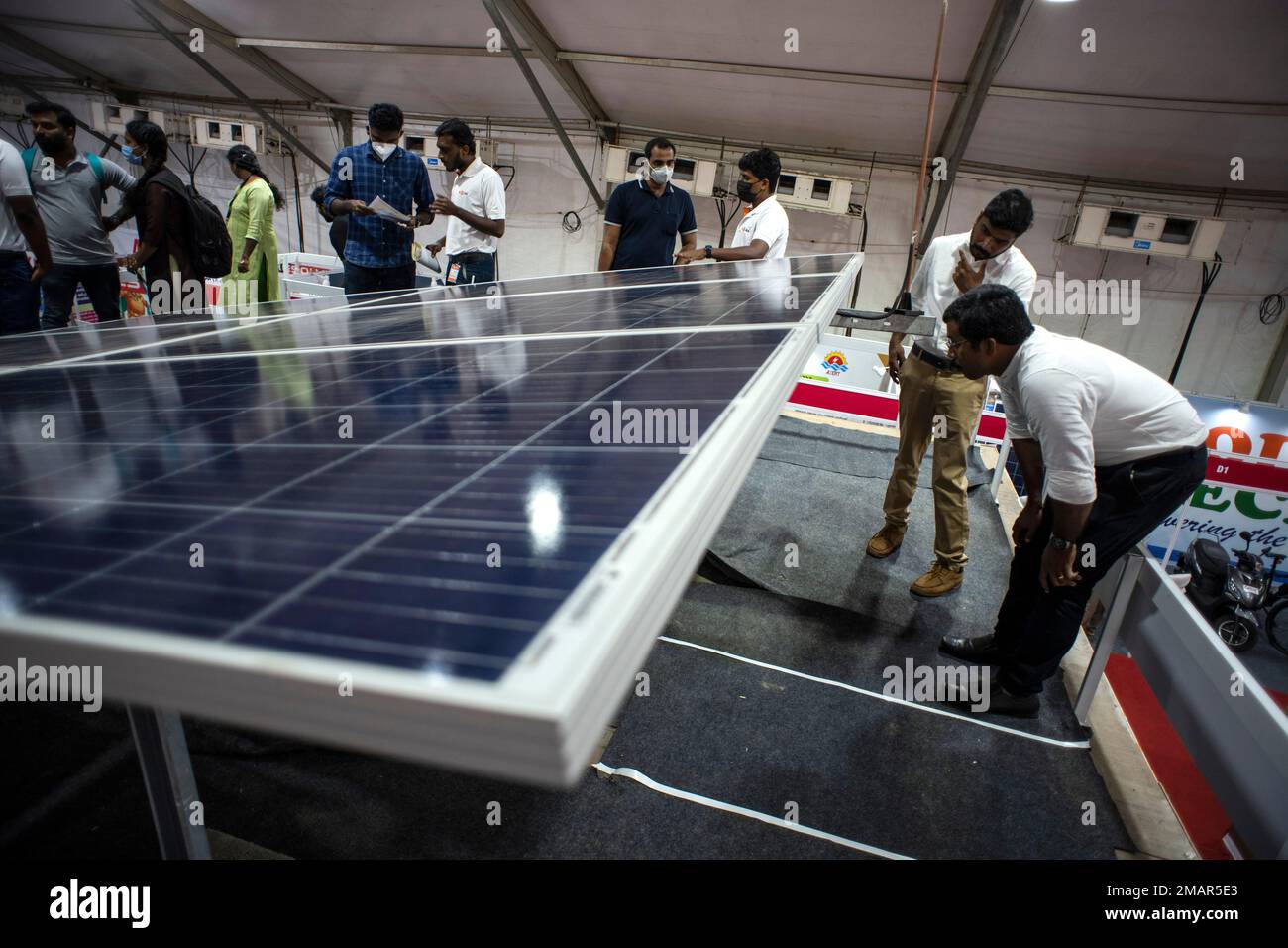 Visitors look at a solar panel on display at an exhibition of renewable ...