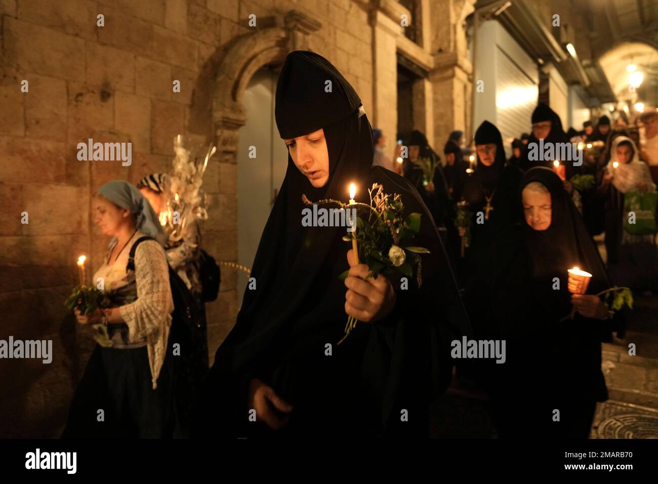 Christian orthodox nuns hold candles and flowers as they walk in a ...