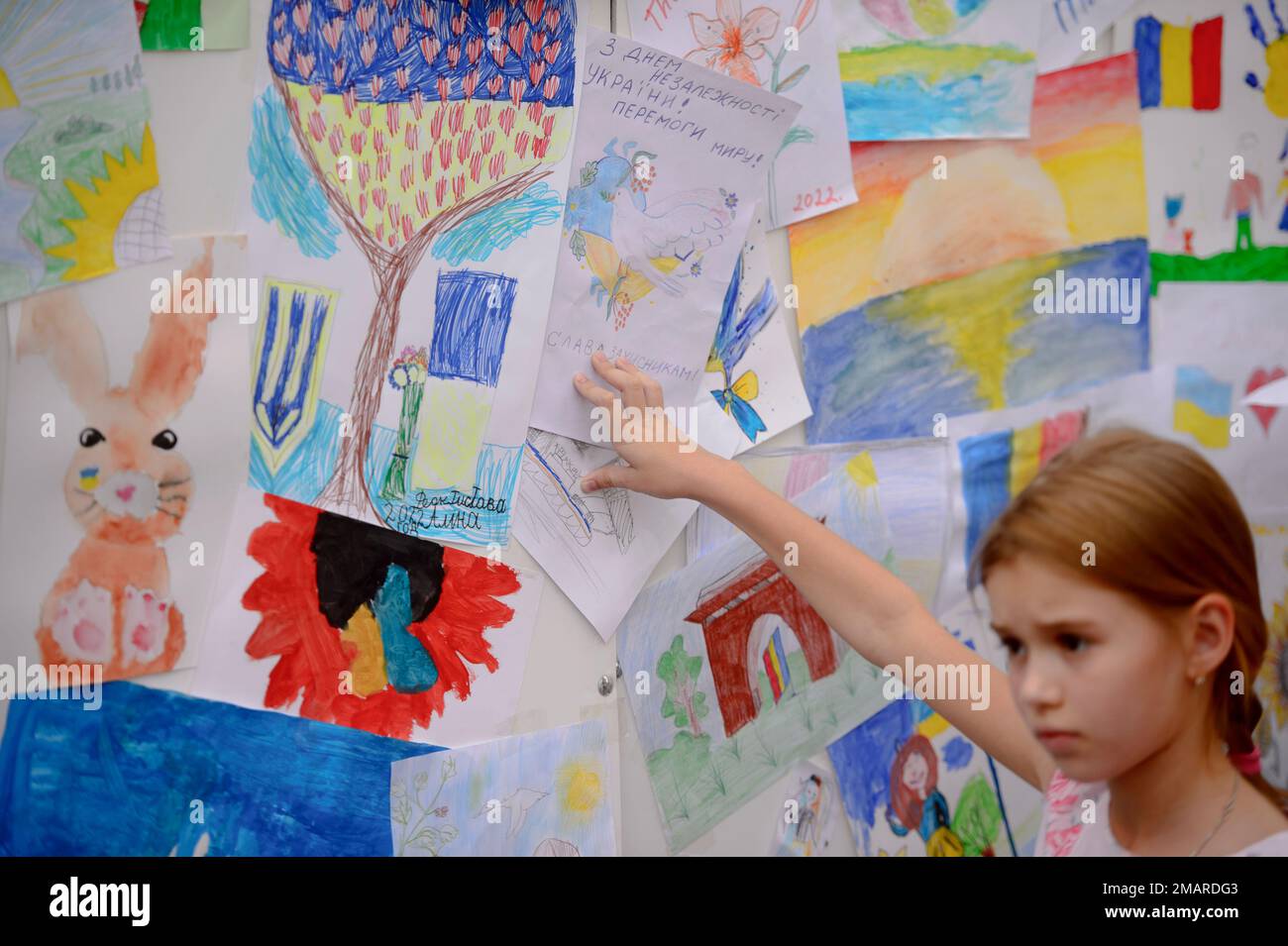 A girl touches drawings by Ukrainian refugee children during an event ...
