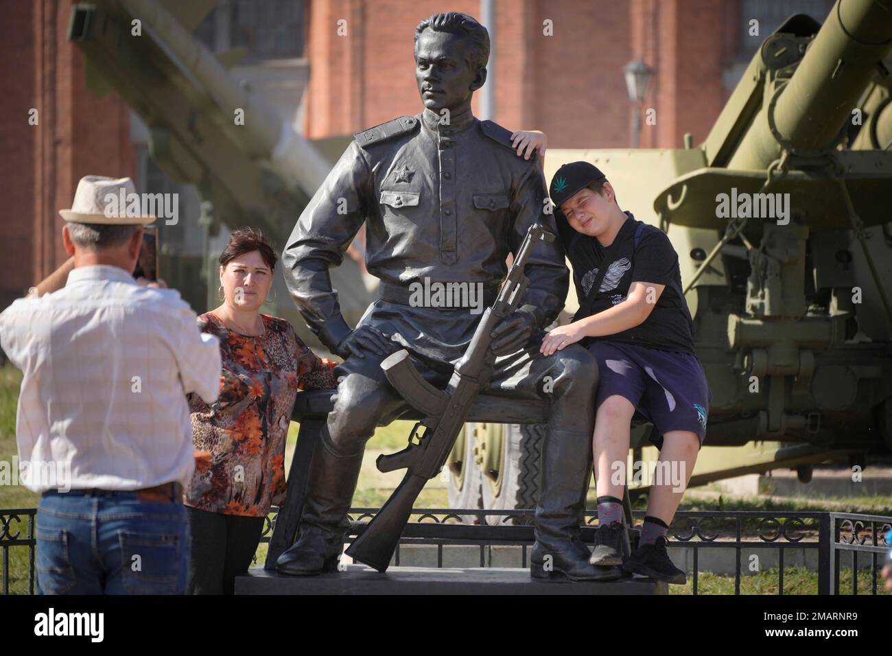 People pose for photo at a sculpture of Mikhail Kalashnikov, a creator ...