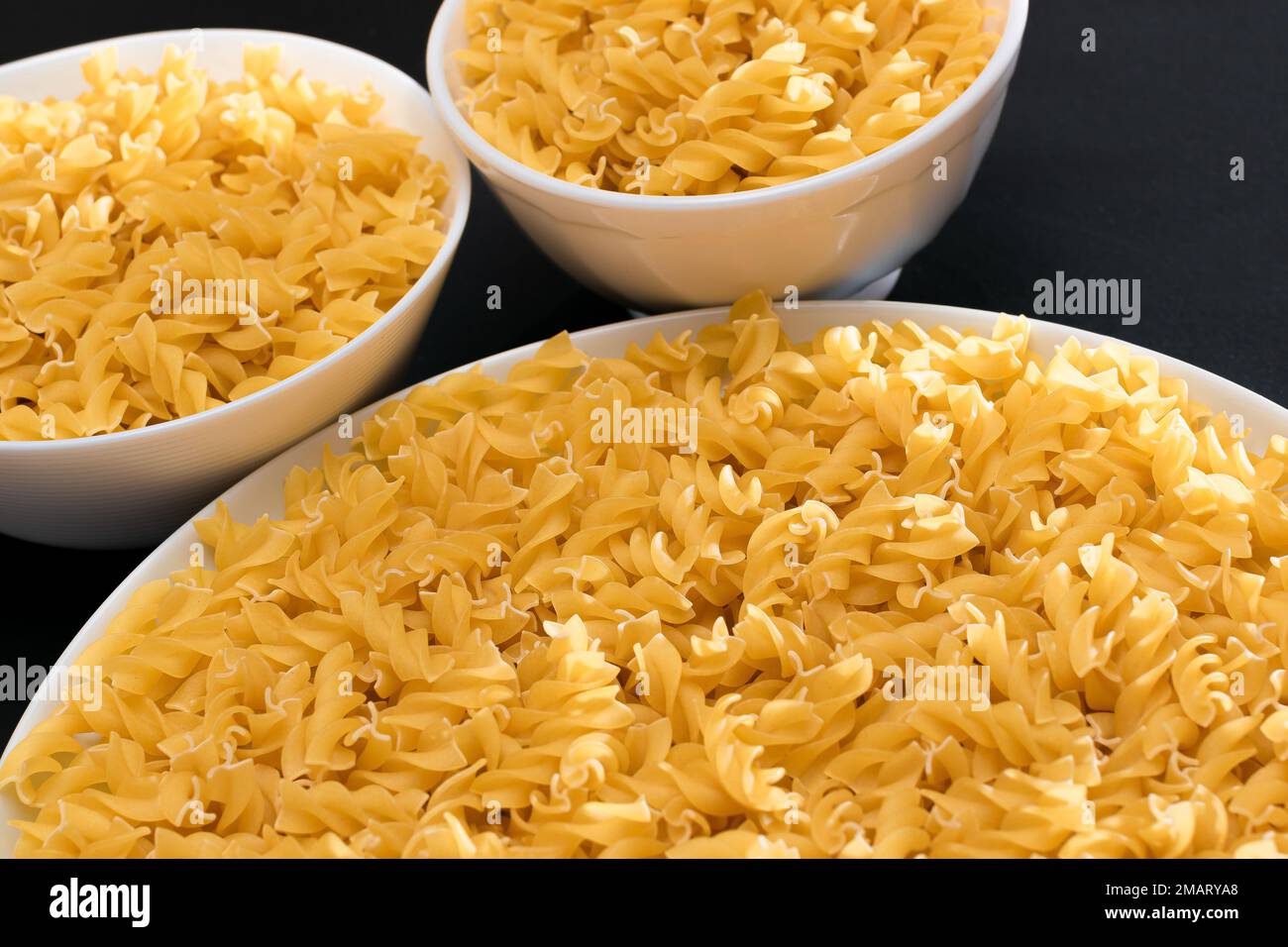 Uncooked Fusilli Pasta Lying on White Plate on Black Background. Raw ...