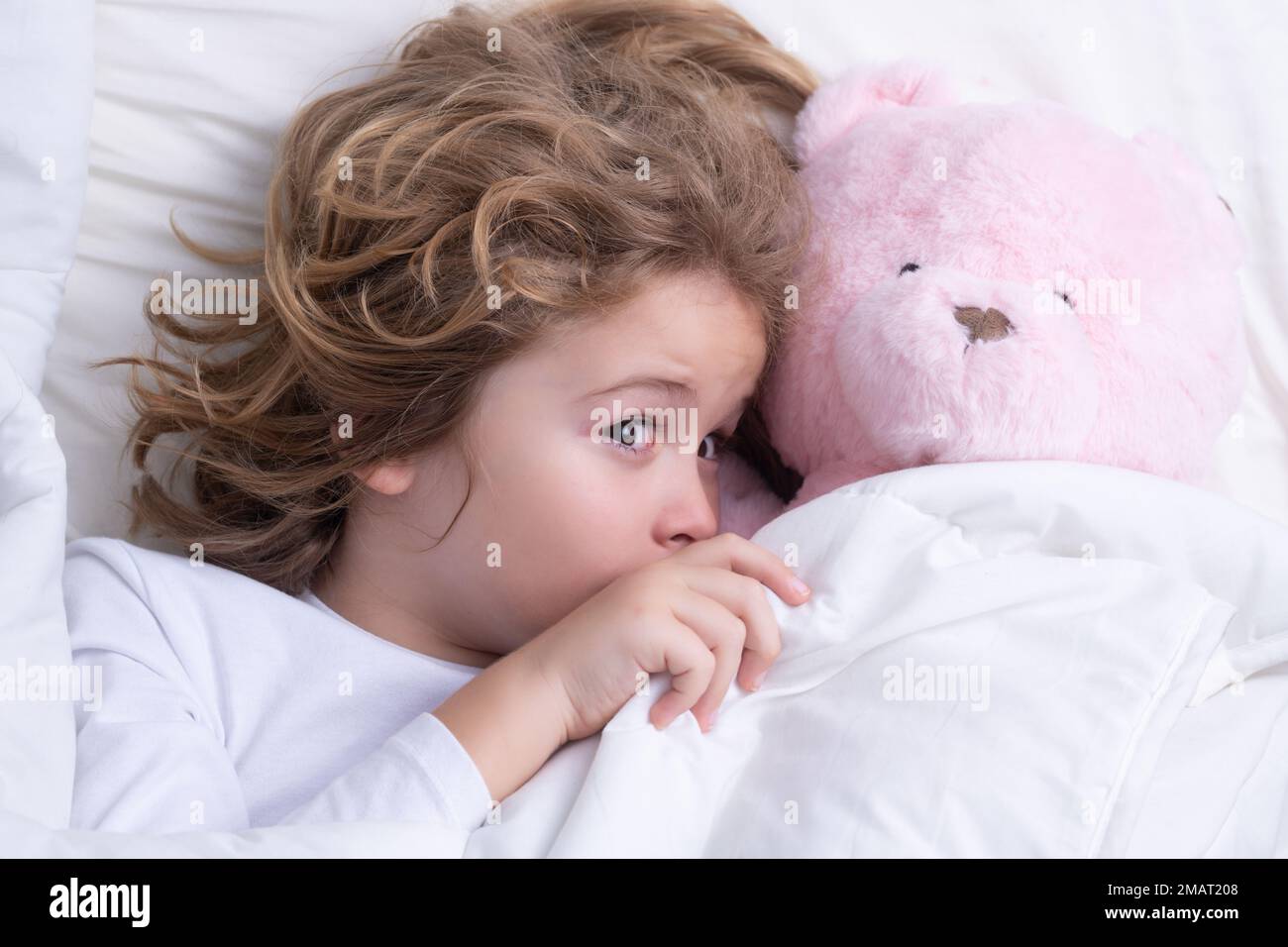Child wakes up with toy teddy bear in the morning in the bedroom. Cute ...