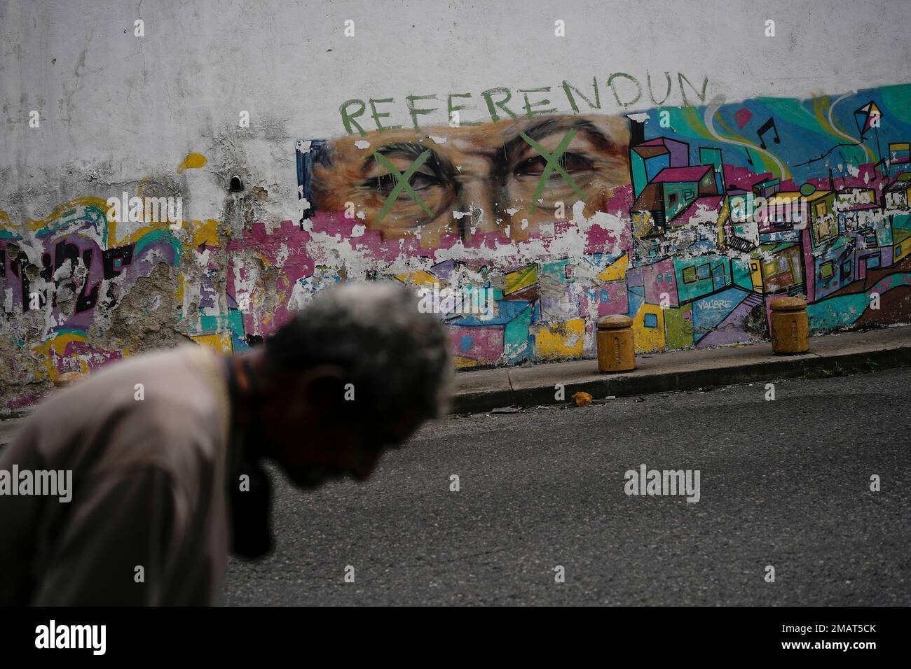A man walks past a defaced mural that depicts "Chavez's eyes", a design ...