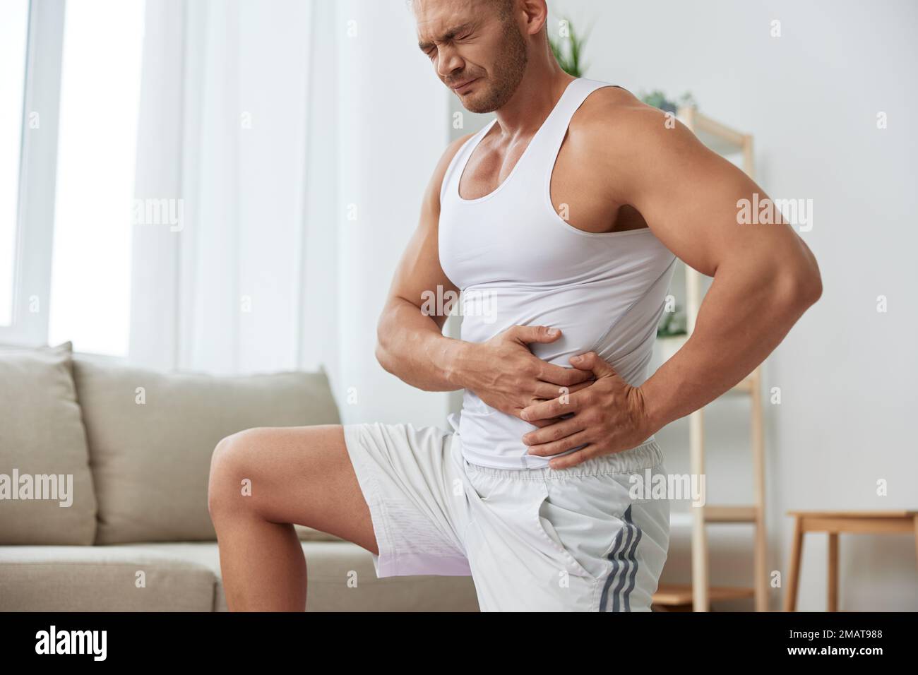 Man sports pain in the side and leg during a workout at home, pumped up ...
