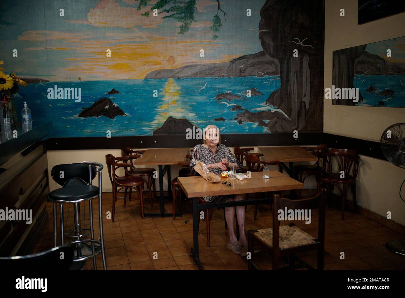 A woman sits in a bar on a hot day in Marseille, southern France ...