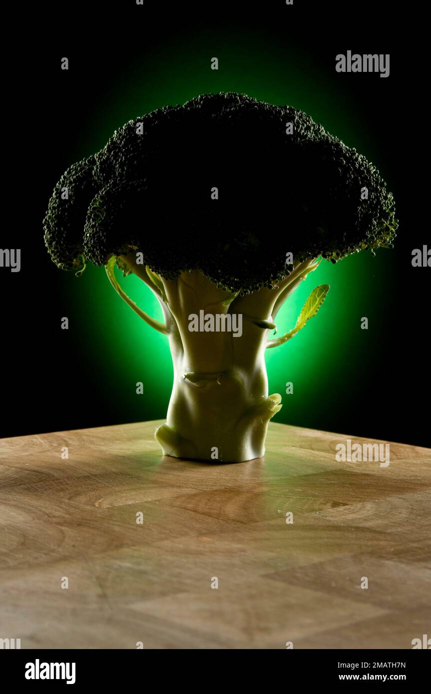 Whole broccoli head on timber bench low key side lit with green spot on ...