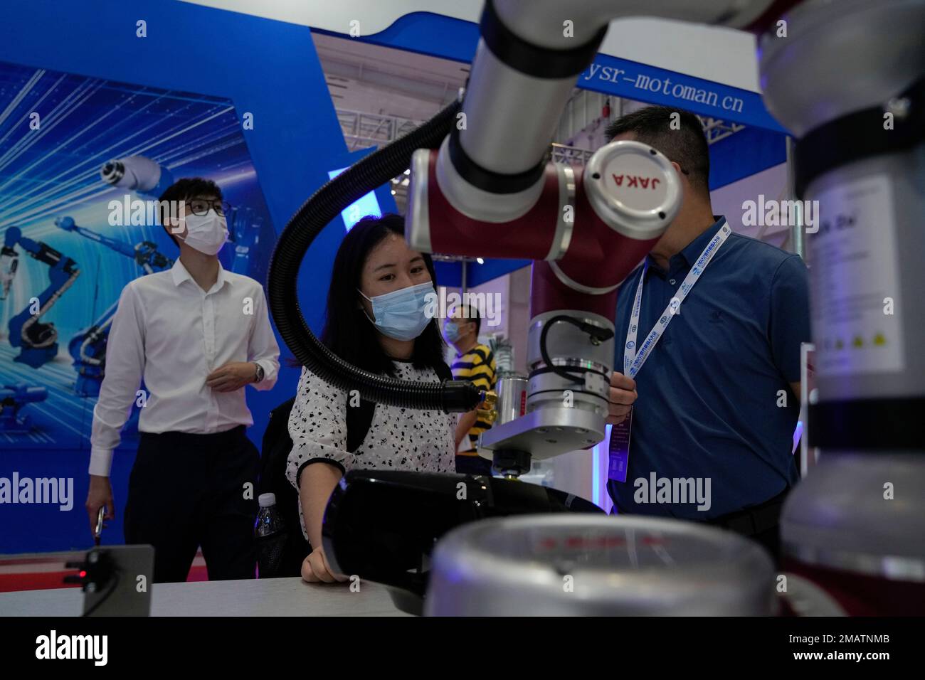 Visitors look at a Chinese-made industrial robot during the World Robot ...
