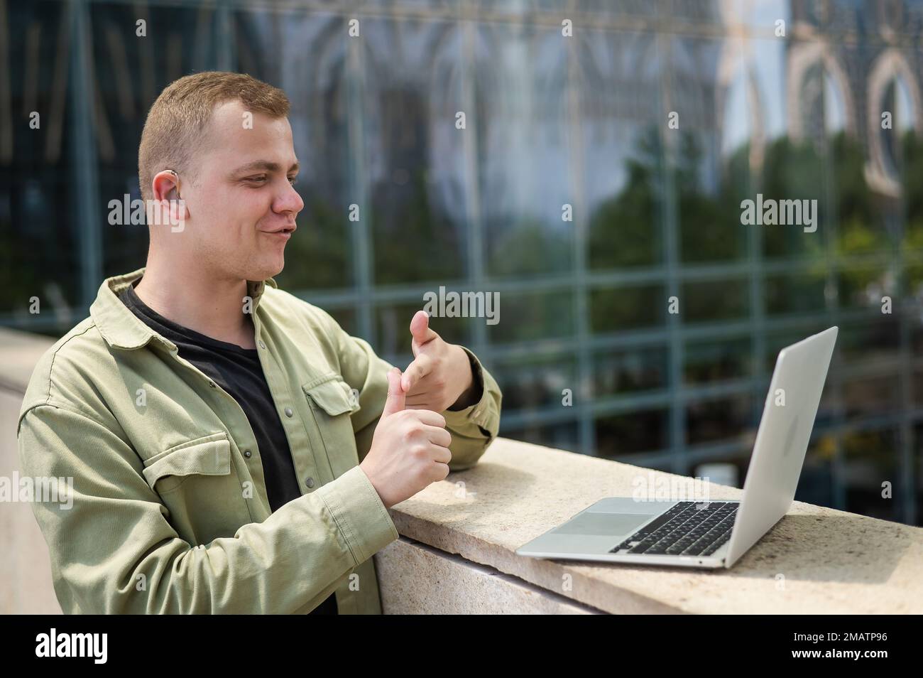 Caucasian man communicates in sign language via video link on laptop ...