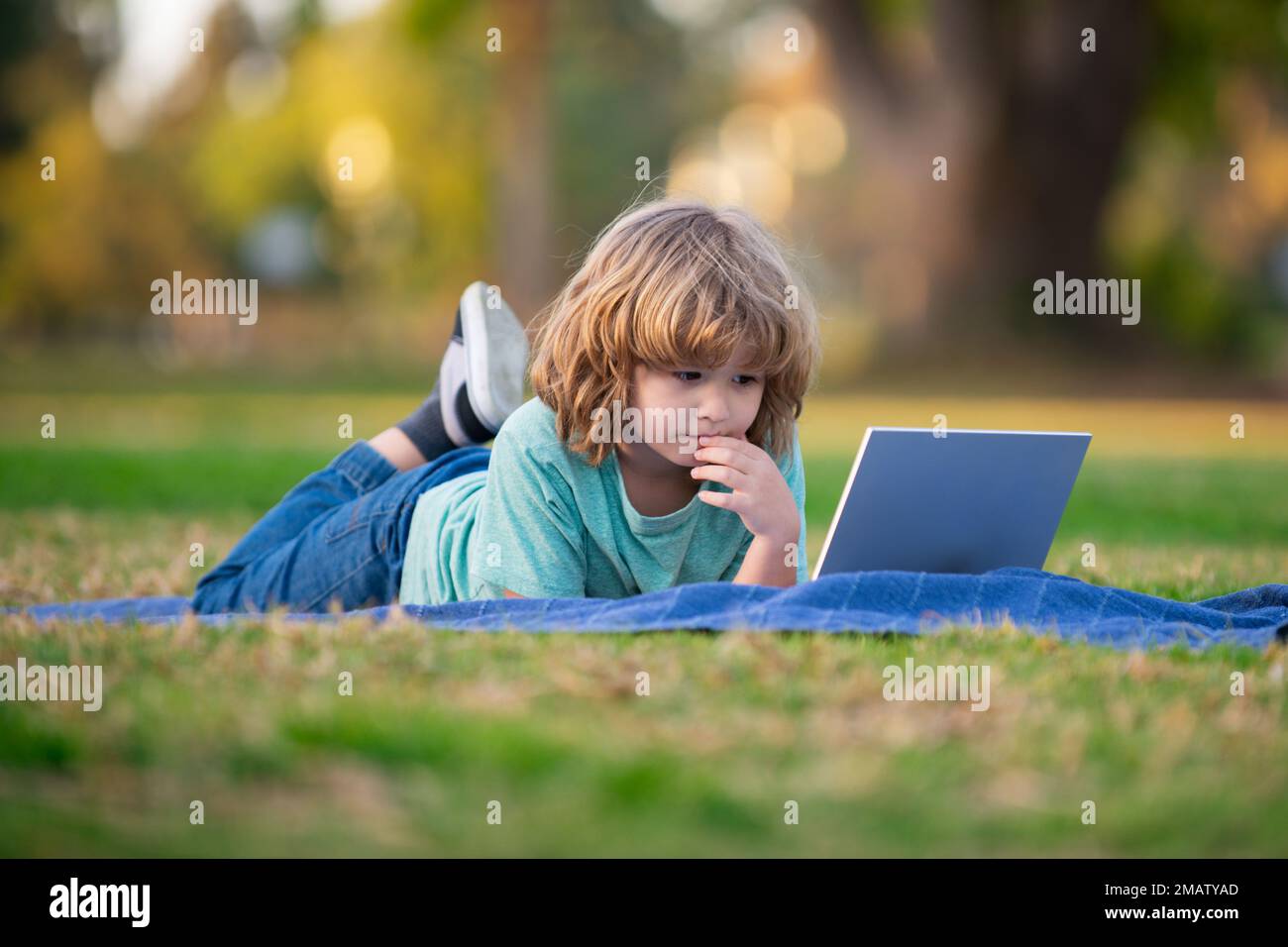School boy in park outdoor doing school homework. Child using laptop ...