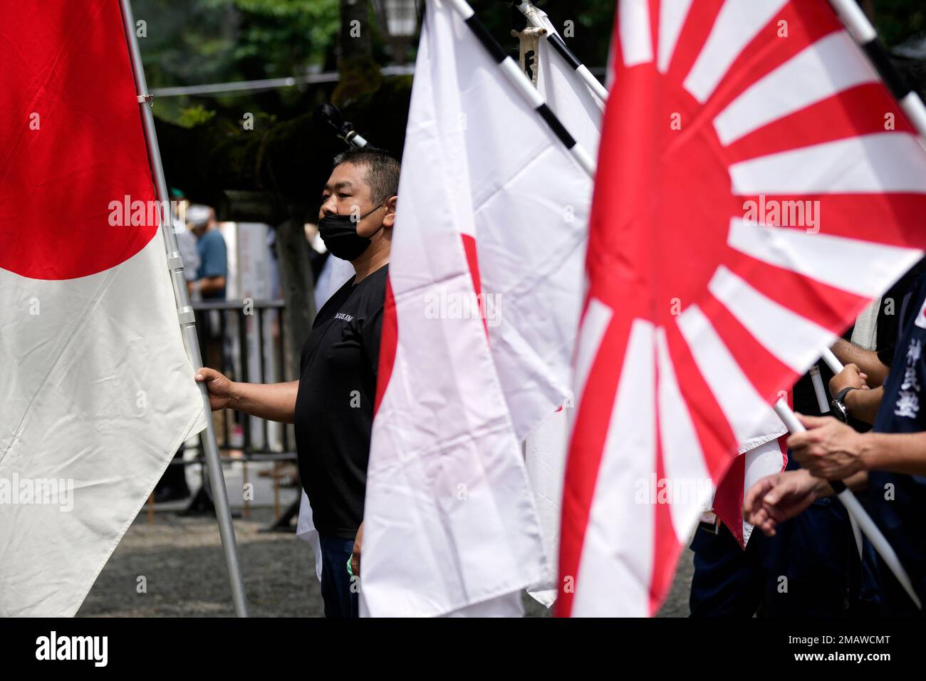 Visitors carry Japanese flags and a rising sun flag at Yasukuni Shrine ...